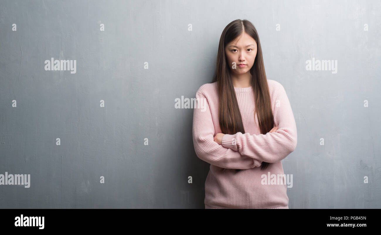Young Chinese woman over grey wall skeptic and nervous, disapproving ...