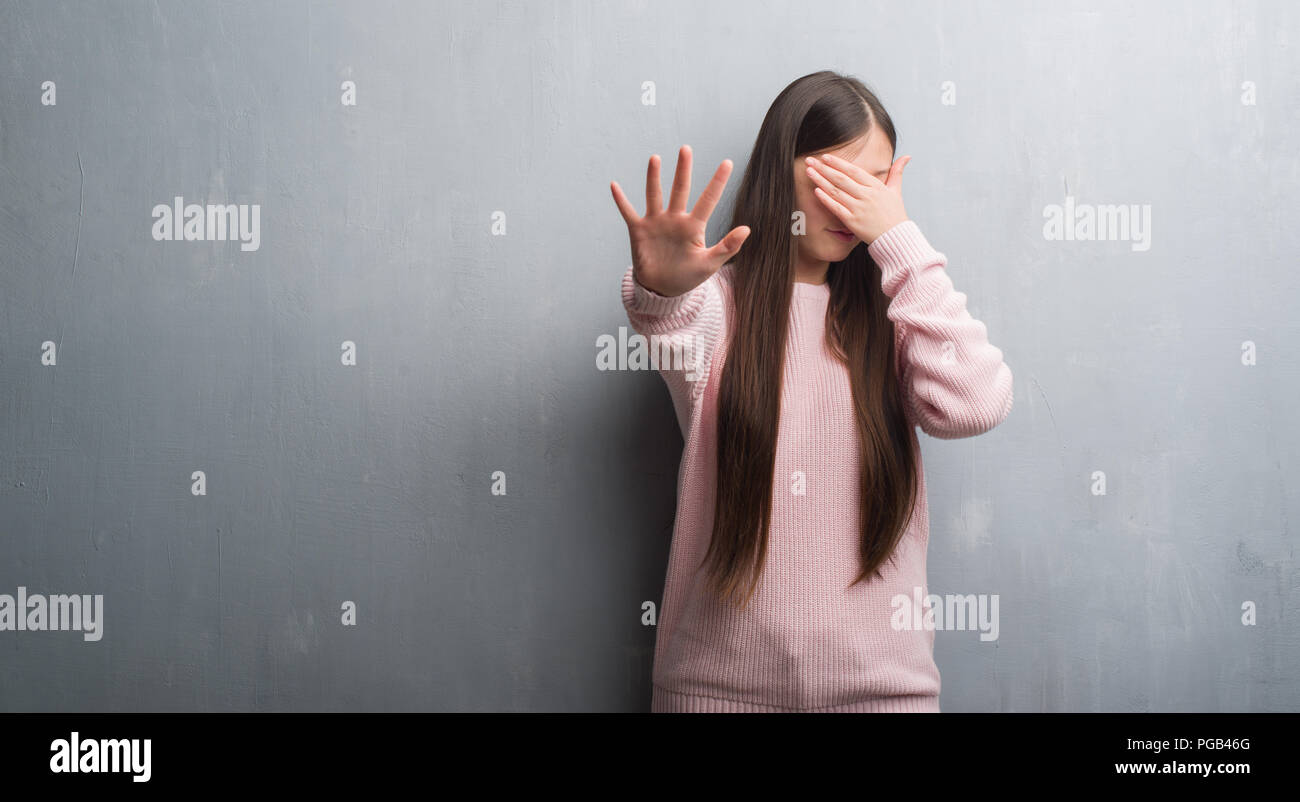 Young Chinese woman over grey wall covering eyes with hands and doing ...