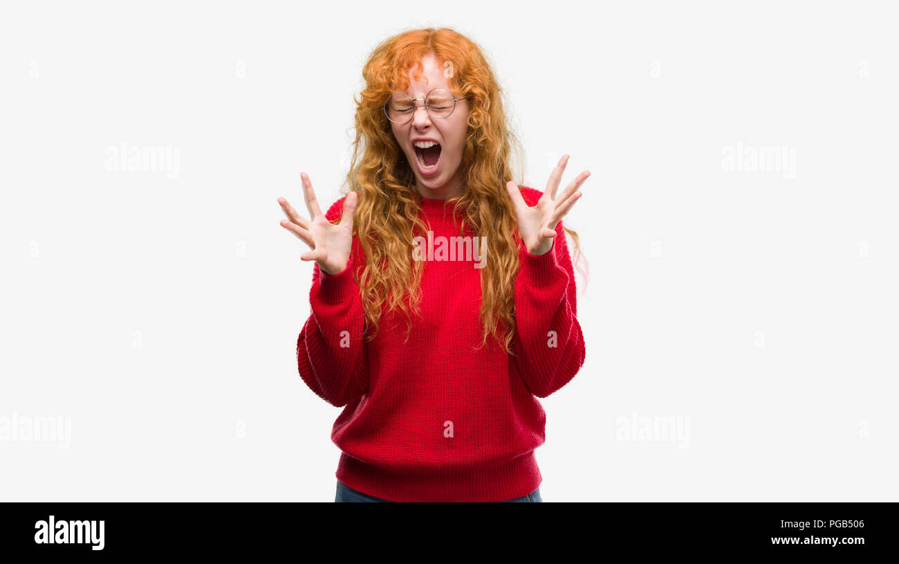 Young redhead woman wearing red sweater celebrating mad and crazy for ...