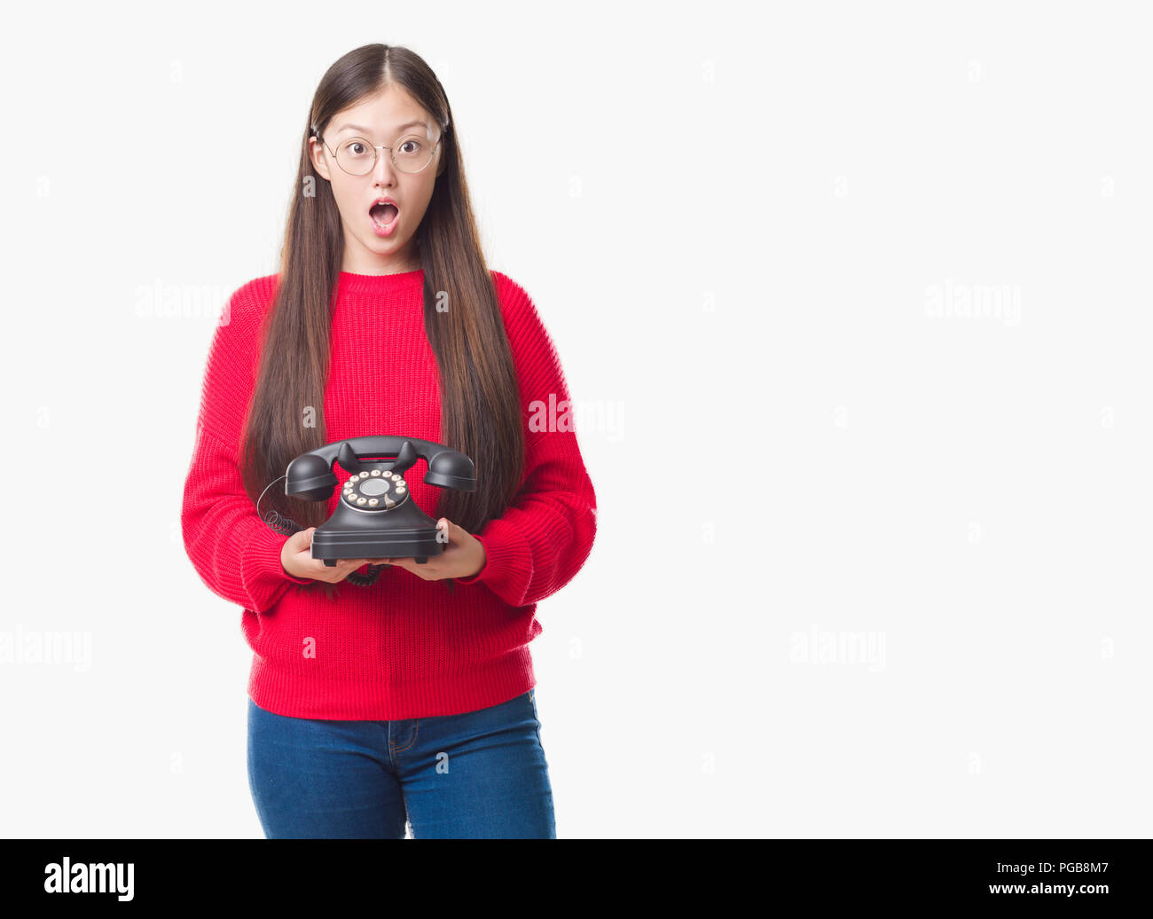 Young Chinese woman over isolated background holding vintage telephone ...
