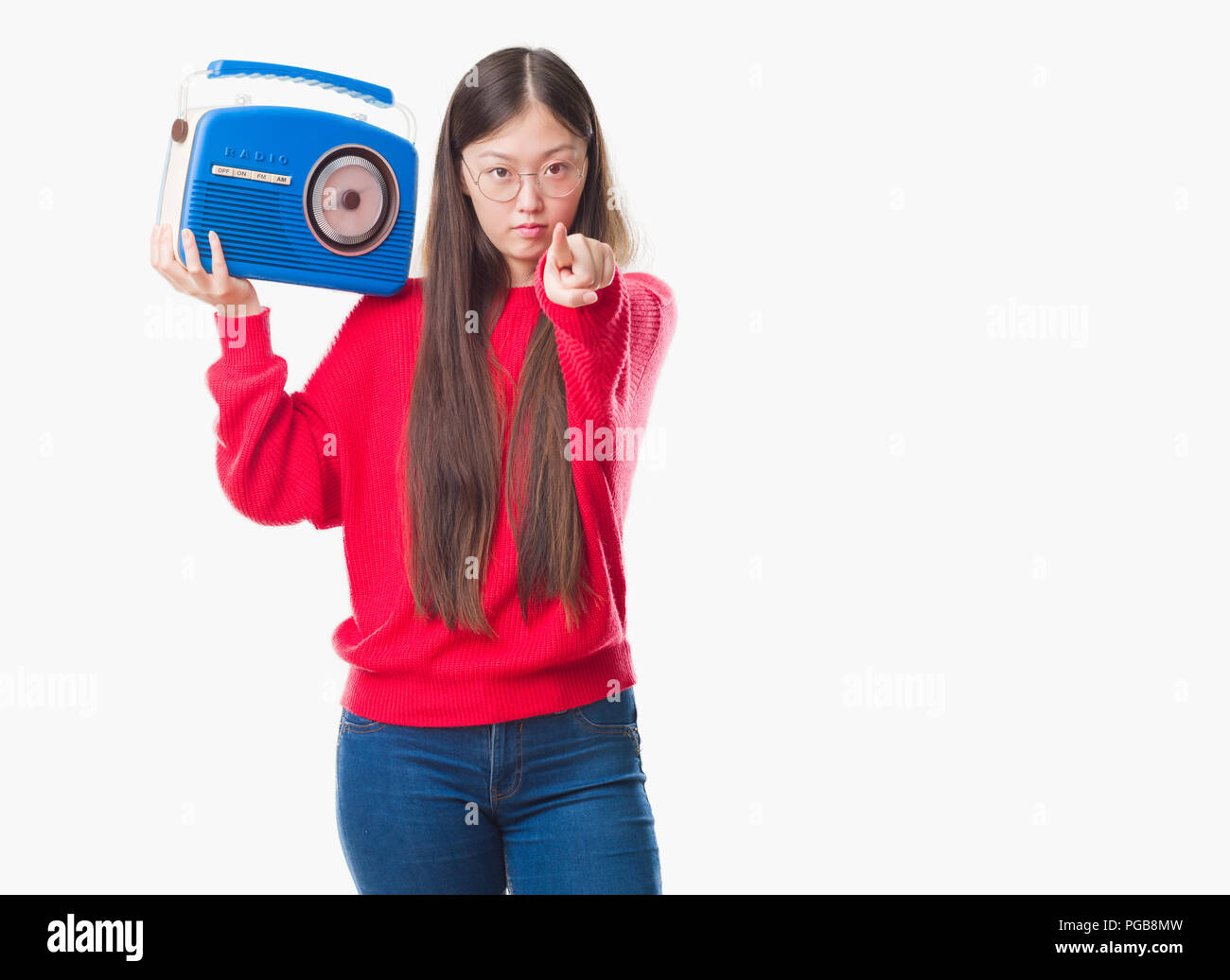 Young Chinese woman over isolated background holding vintage radio ...