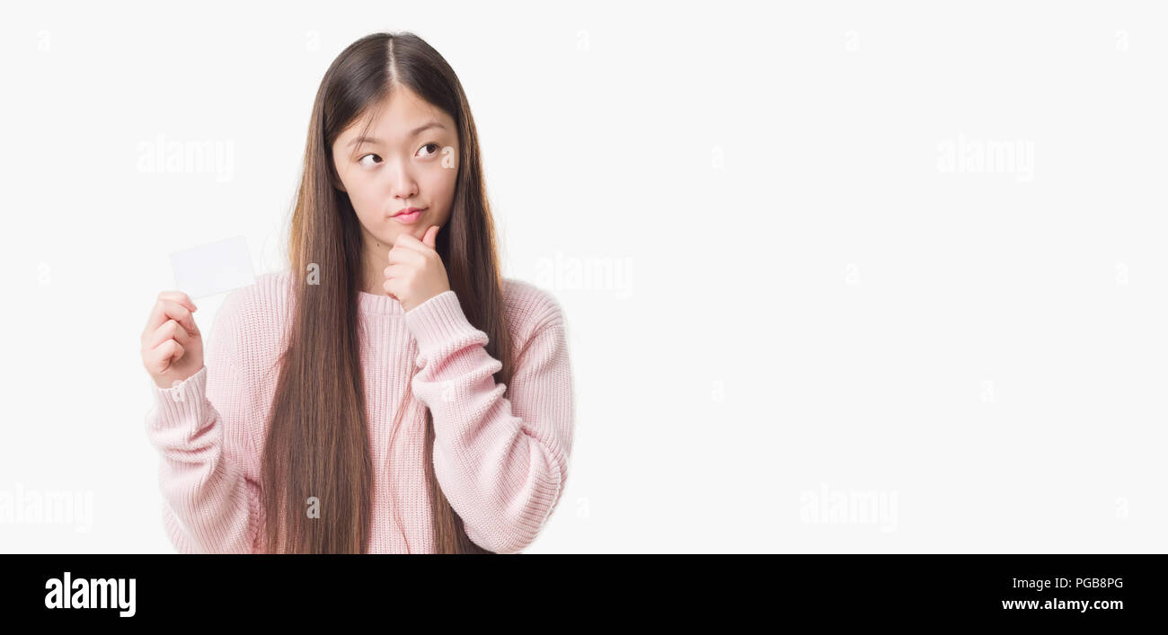 Young Chinese woman over isolated background holding visit card serious ...
