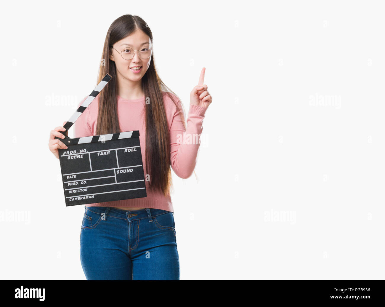 Young Chinese woman over isolated background holding clapper surprised ...