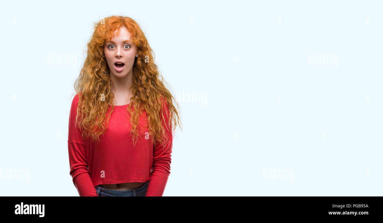 Young redhead woman scared in shock with a surprise face, afraid and ...
