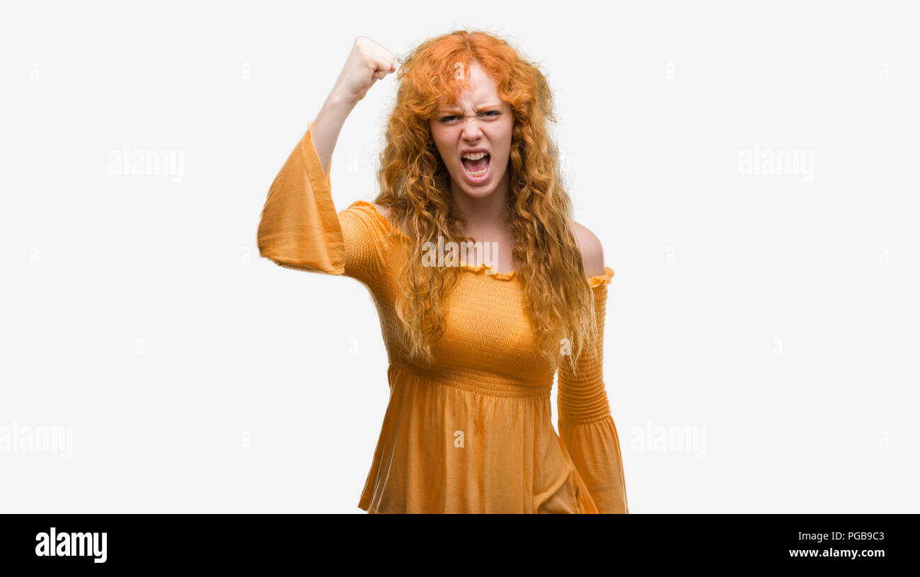 Young redhead woman angry and mad raising fist frustrated and furious ...