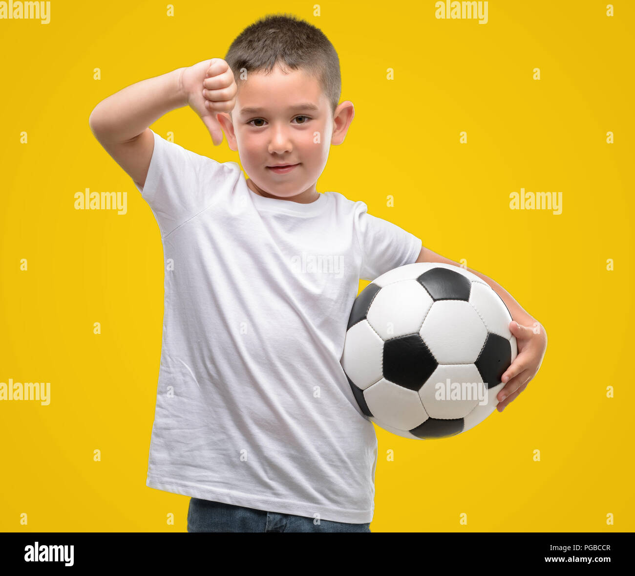 Dark haired little child playing with soccer ball with angry face ...