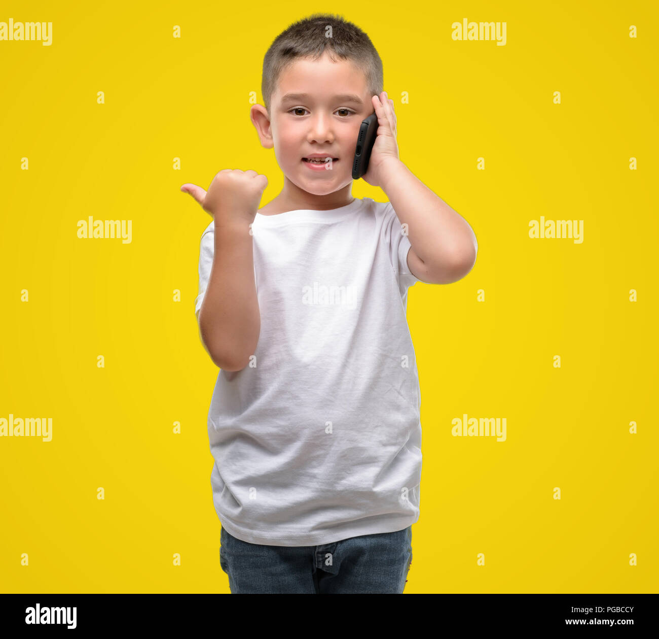 Dark haired little child using a smartphone pointing with hand and ...