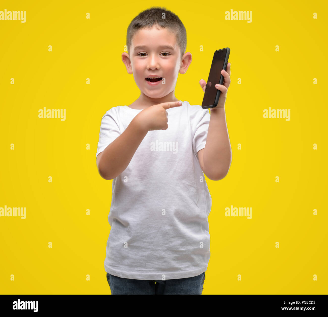 Dark haired little child using a smartphone very happy pointing with ...