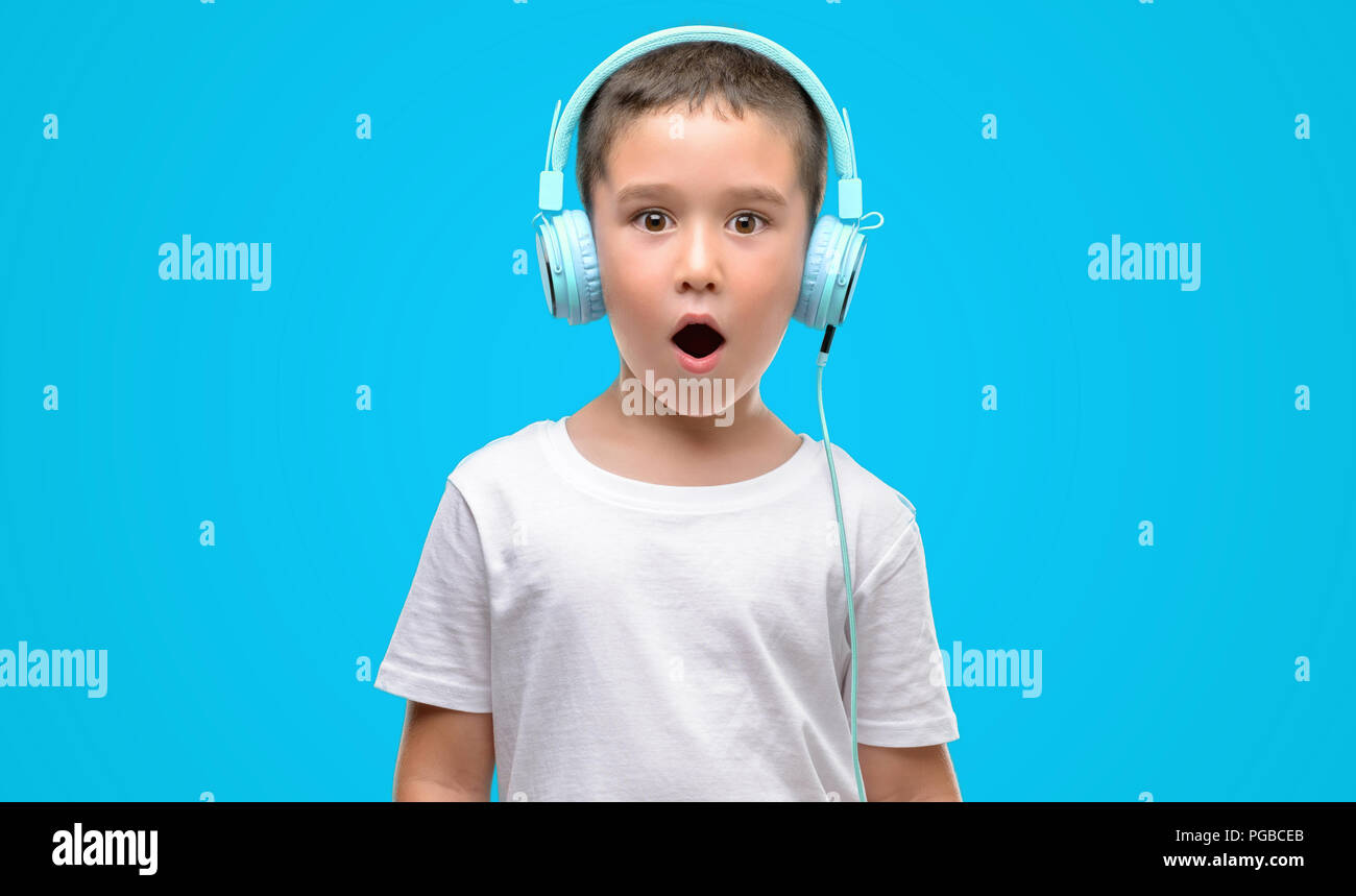 Dark haired little child listening music with headphones scared in ...