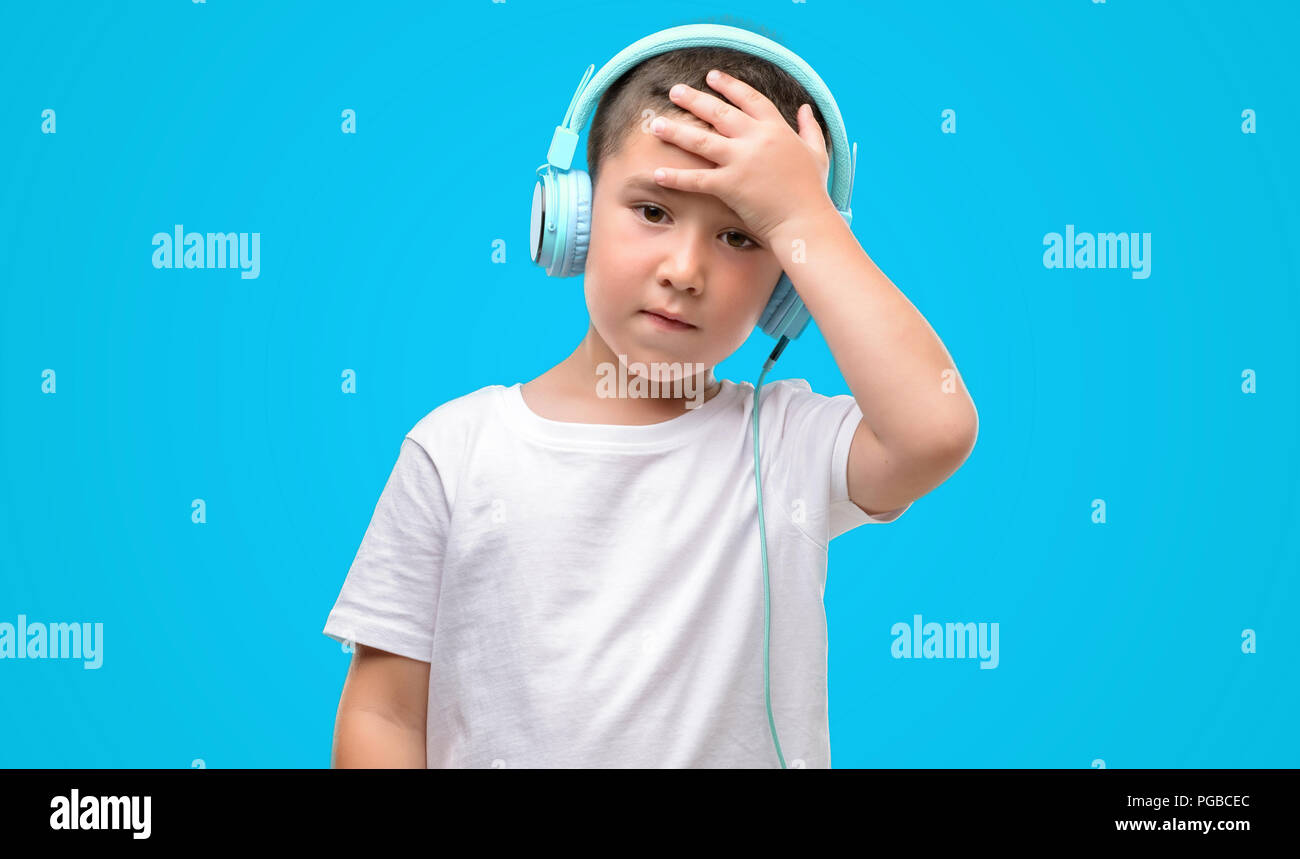 Dark haired little child listening music with headphones stressed with ...