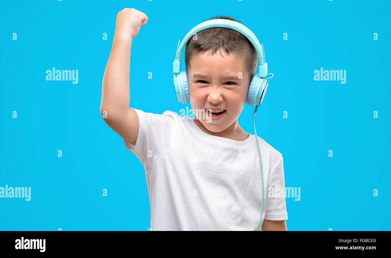 Dark haired little child listening music with headphones annoyed and ...