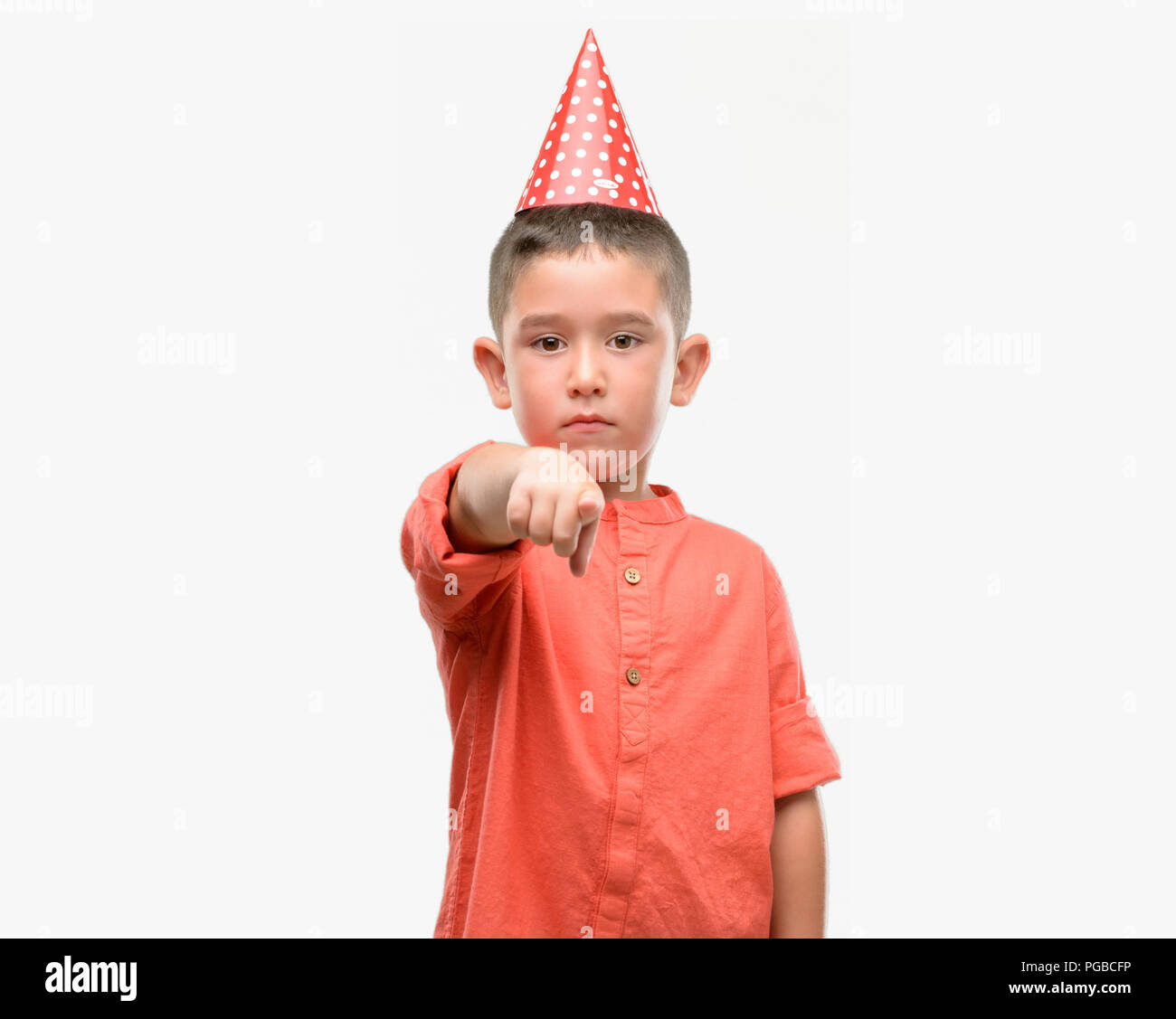 Dark haired little child wearing birthday cap pointing with finger to ...