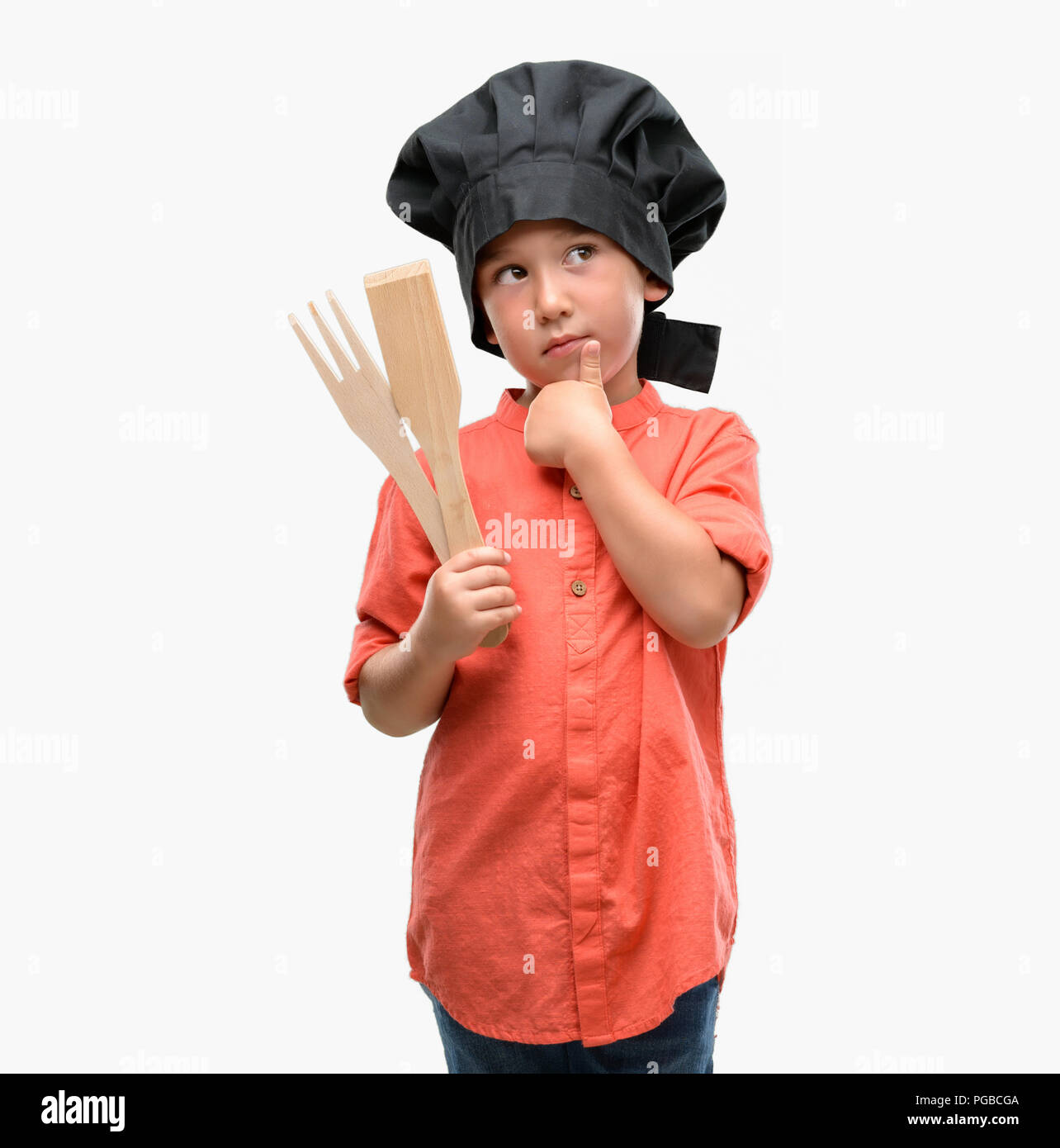 Dark haired little child wearing chef uniform serious face thinking ...