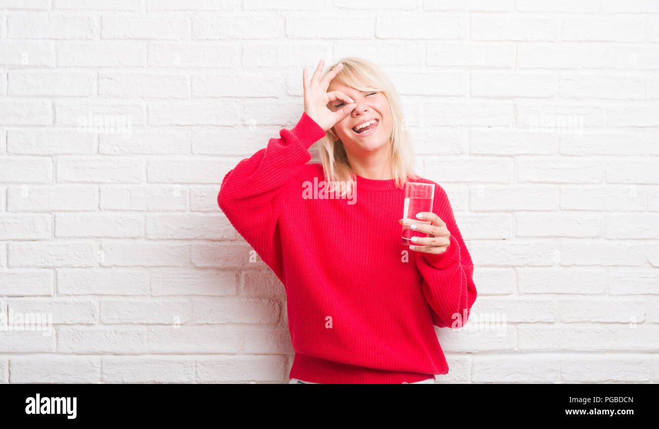 Adult Caucasian Woman Over White Brick Wall Drinking A Glass Of Water