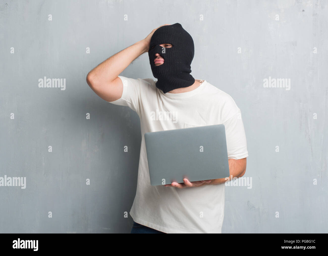 Young caucasian hacker man over grey grunge wall doing cyber attack ...