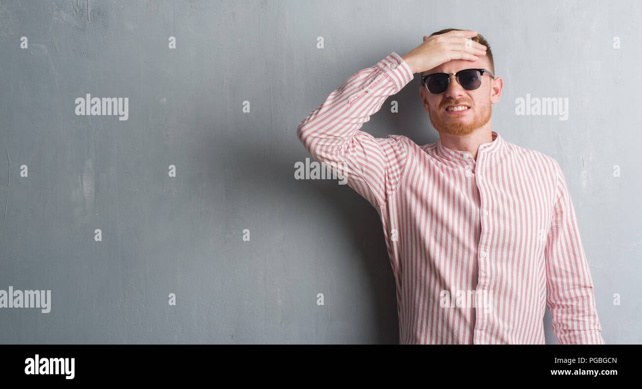 Young Redhead Man Over Grey Grunge Wall Wearing Sunglasses Stressed