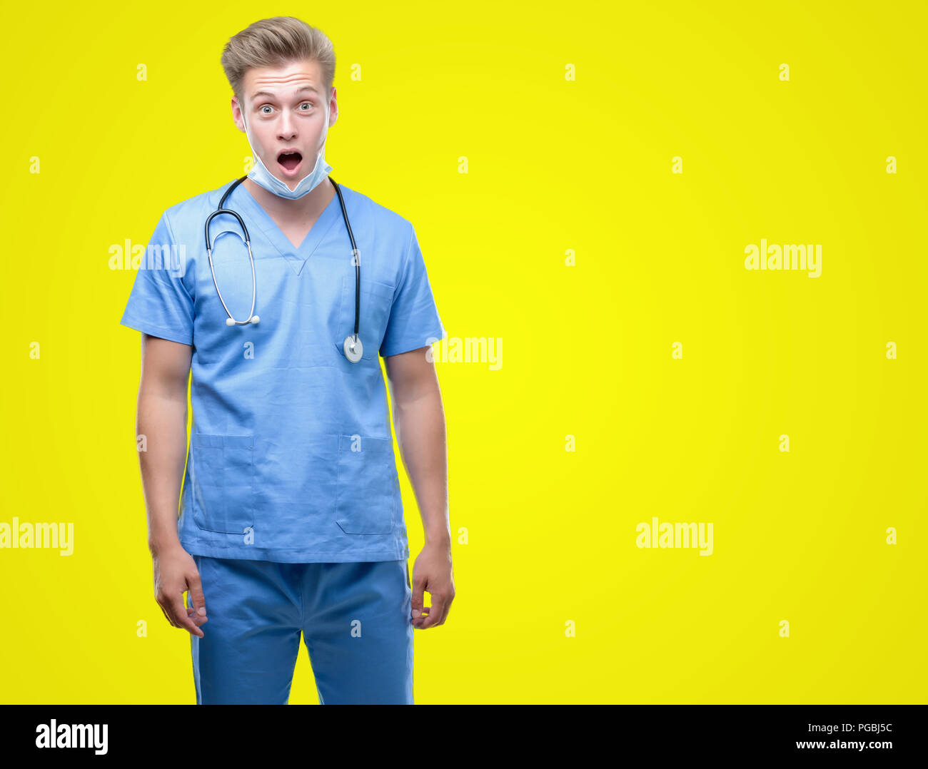Young handsome blond doctor scared in shock with a surprise face ...