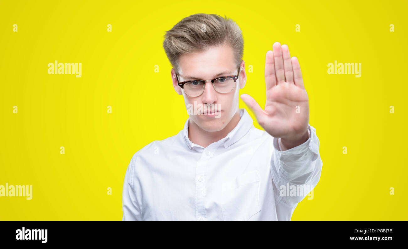Young handsome blond man doing stop sing with palm of the hand. Warning ...