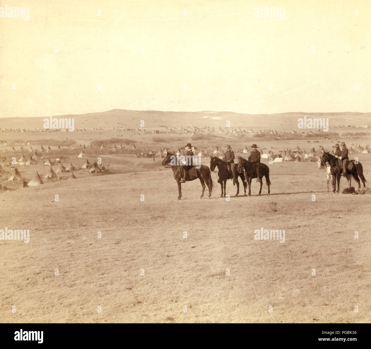 Six military men on horseback on a hill overlooking a large encampment ...