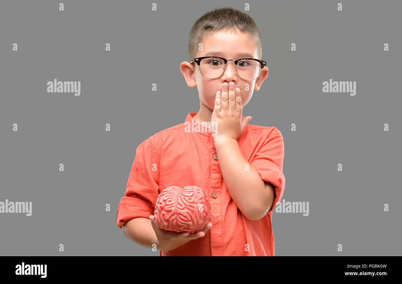 Dark haired little child with glasses holding a brain cover mouth with ...
