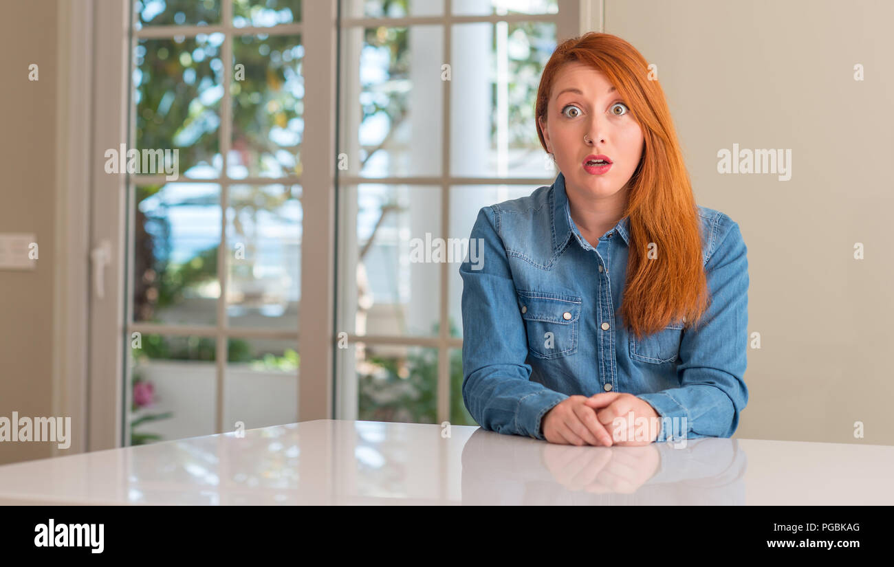Redhead woman at home scared in shock with a surprise face, afraid and ...
