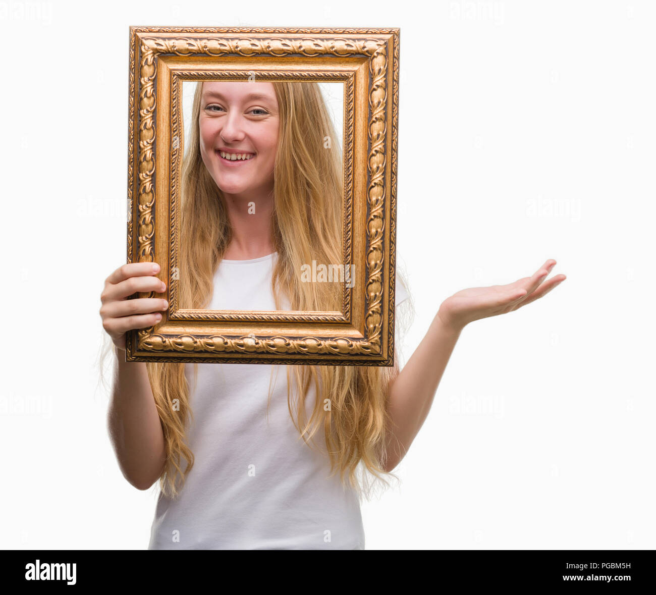 Blonde teenager woman holding vintage frame art very happy and excited ...