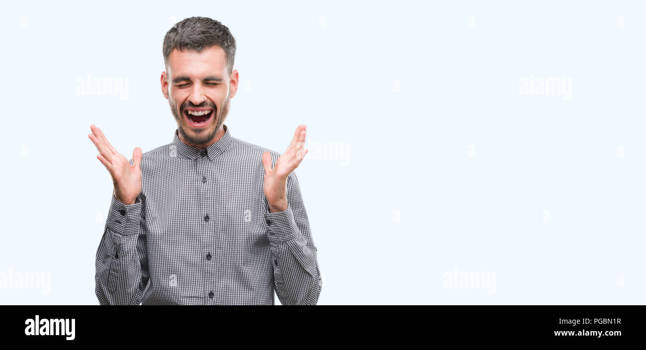 Young hipster man celebrating mad and crazy for success with arms ...