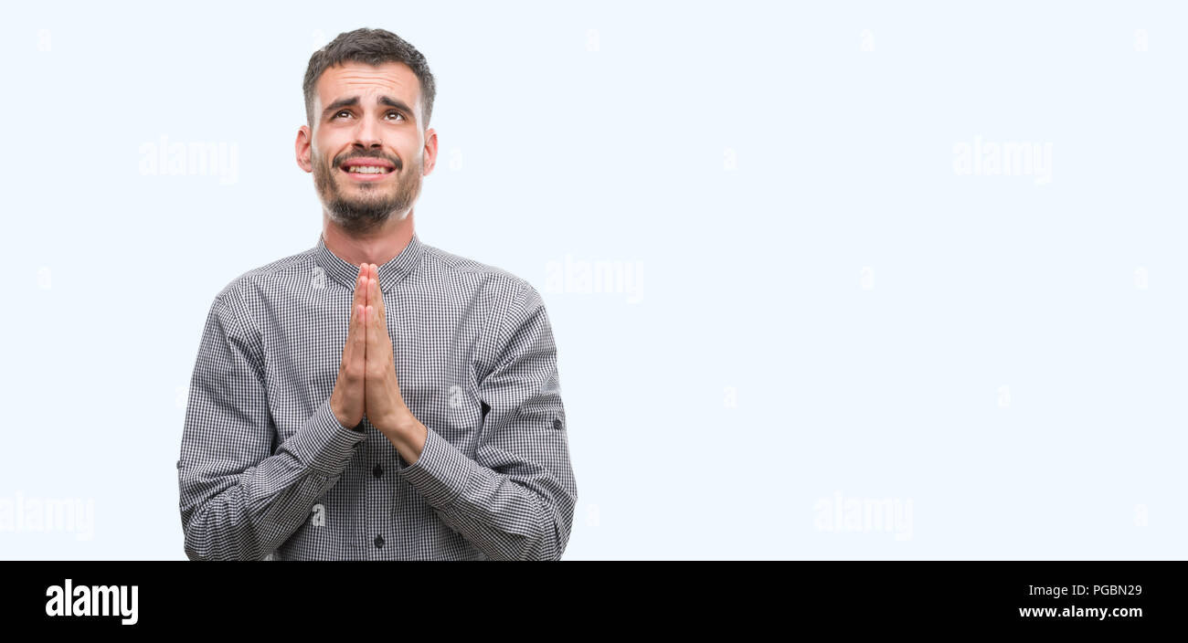 Young hipster man begging and praying with hands together with hope ...