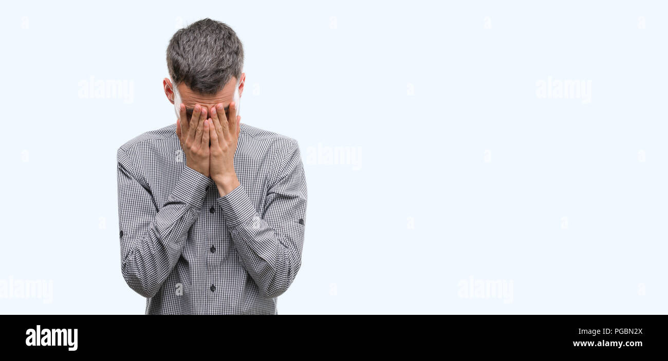 Young hipster man with sad expression covering face with hands while ...