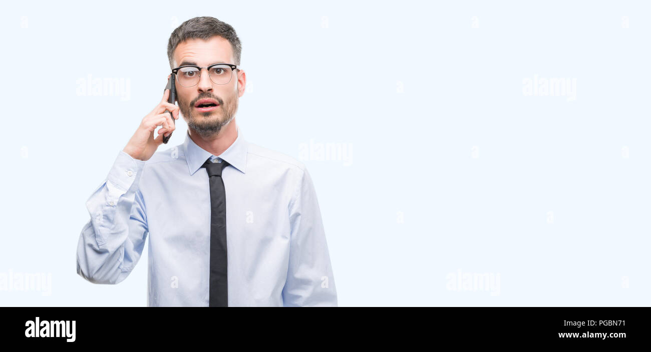 Young business adult man talking on the phone scared in shock with a ...