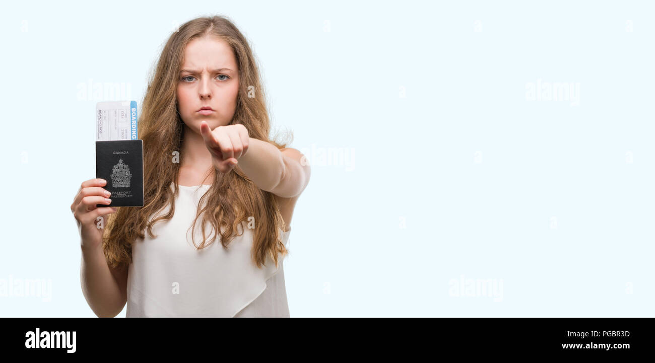 Young blonde woman holding passport of canada and boarding pass ...