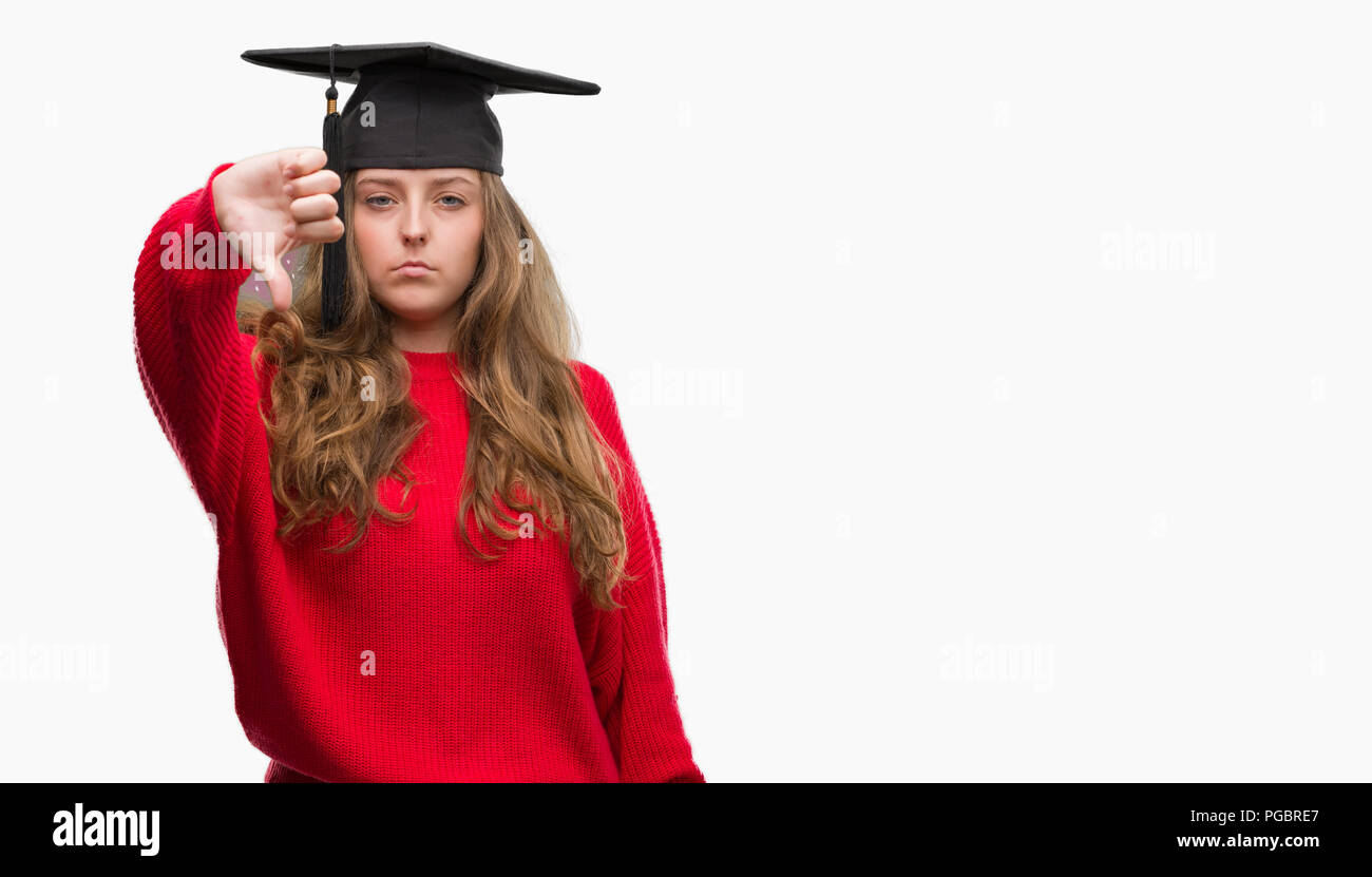 Young blonde woman wearing graduation cap with angry face, negative ...