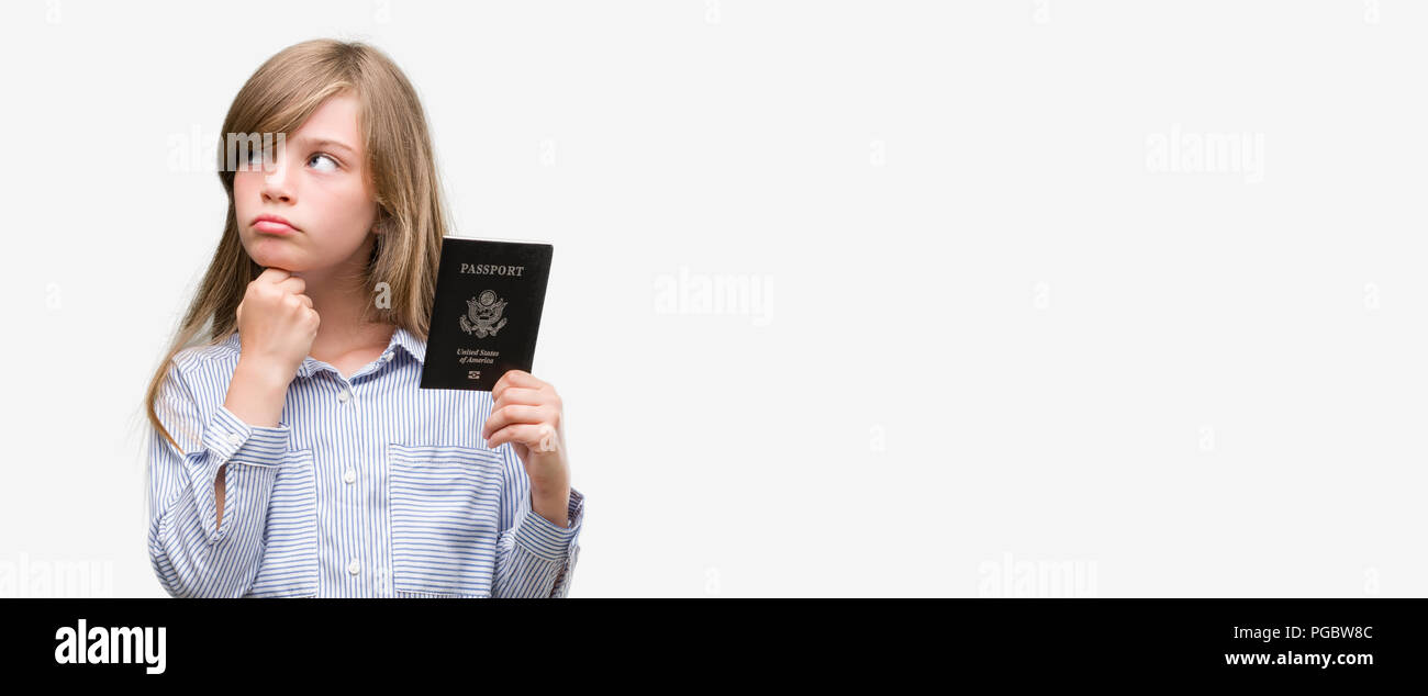 Young blonde toddler holding american passport serious face thinking ...
