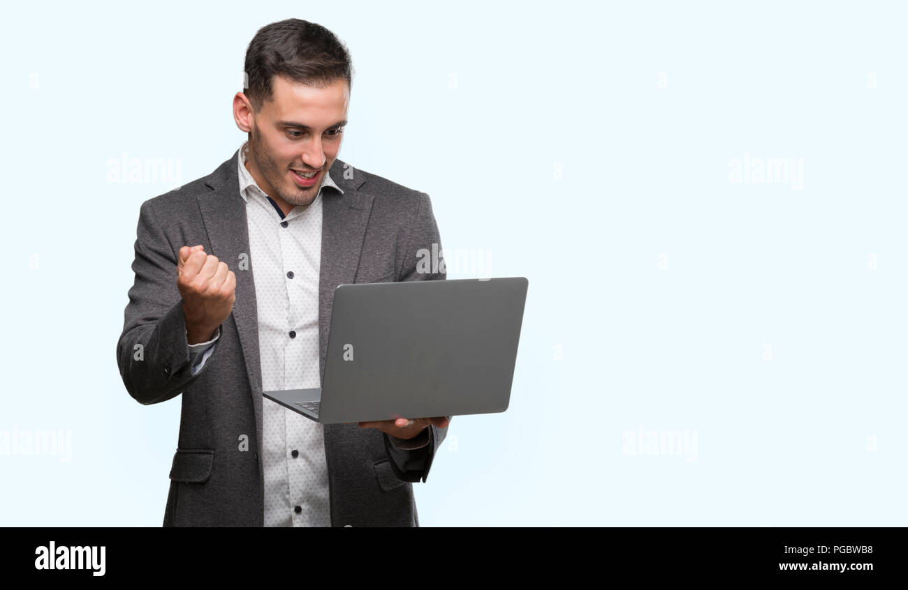 Handsome young man using computer laptop screaming proud and ...