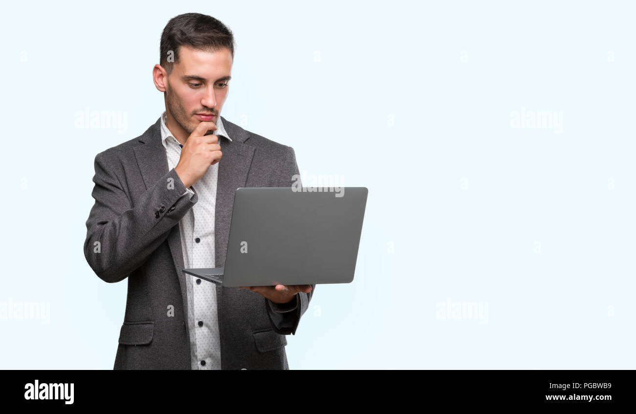 Handsome young man using computer laptop serious face thinking about ...