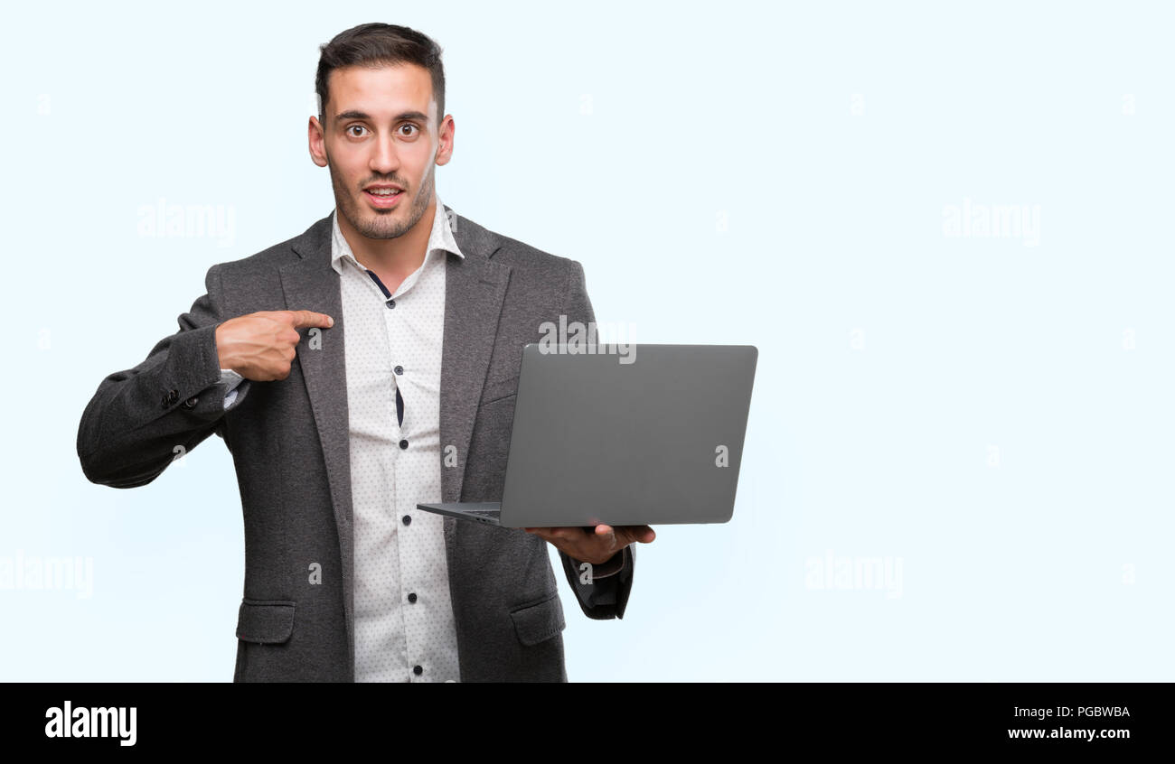 Handsome young man using computer laptop with surprise face pointing ...