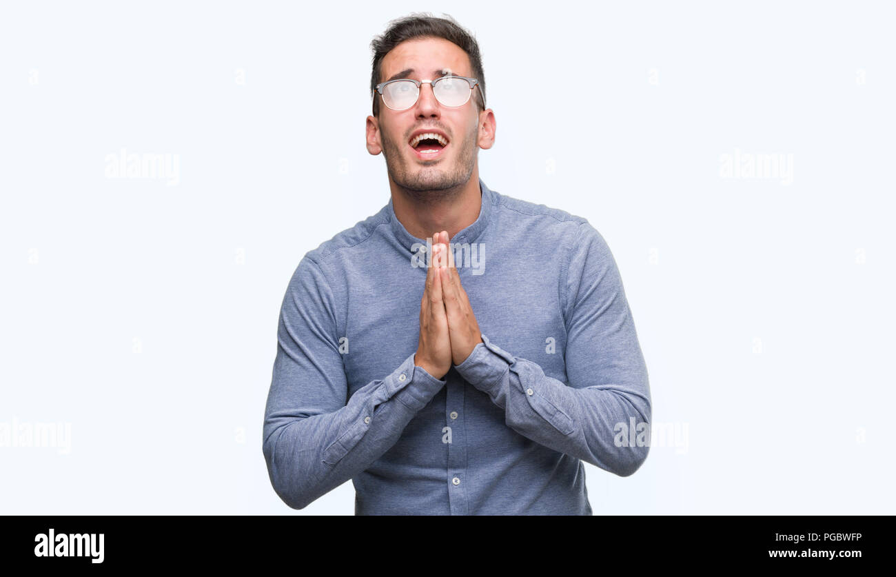 Handsome young elegant man wearing glasses begging and praying with ...