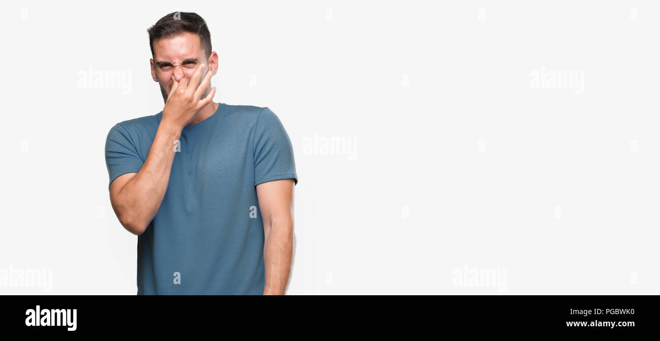 Handsome young casual man smelling something stinky and disgusting ...