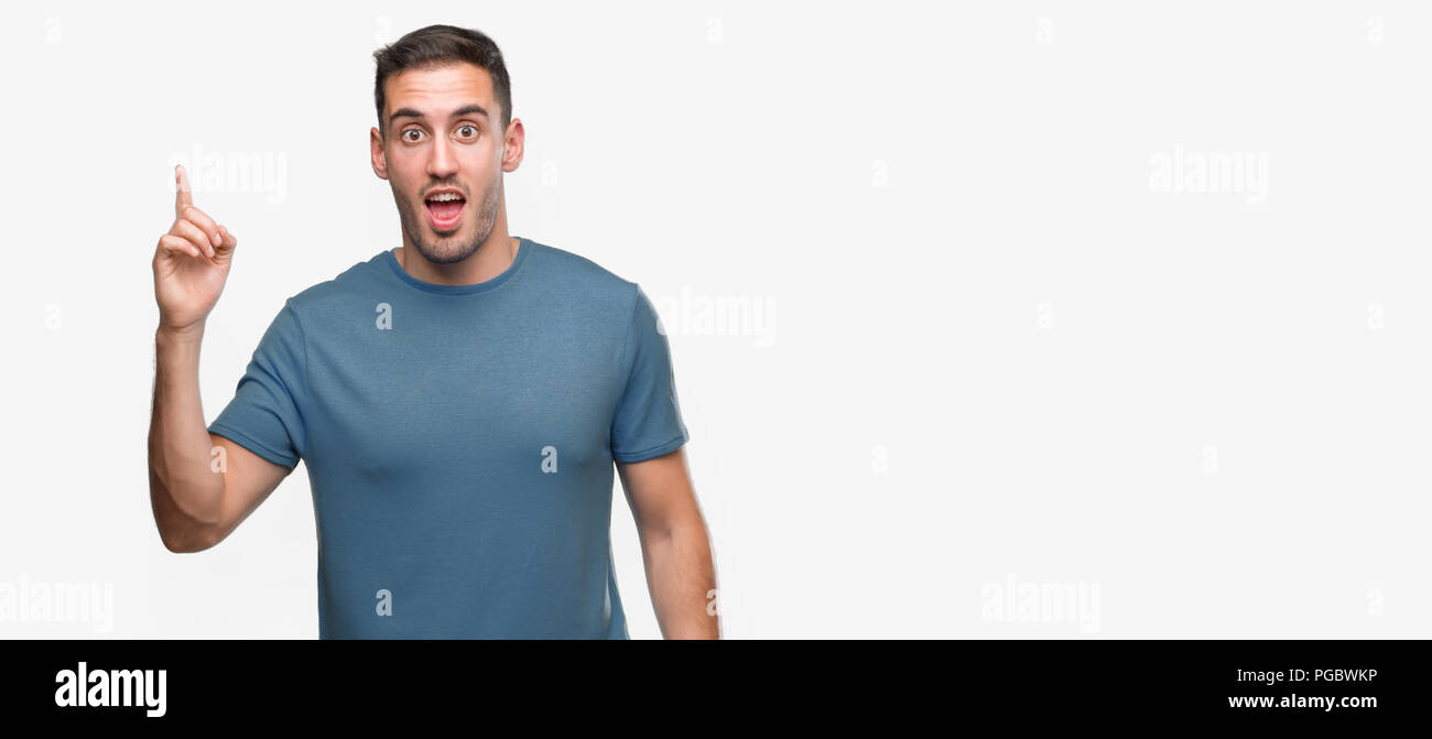 Handsome young casual man pointing finger up with successful idea ...