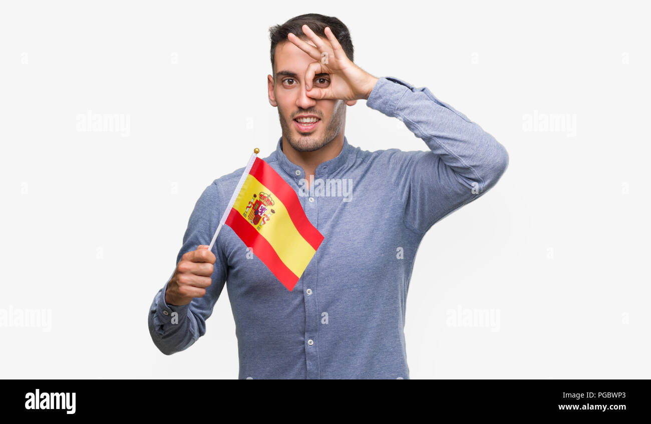 Handsome young man holding a flag of Spain with happy face smiling ...