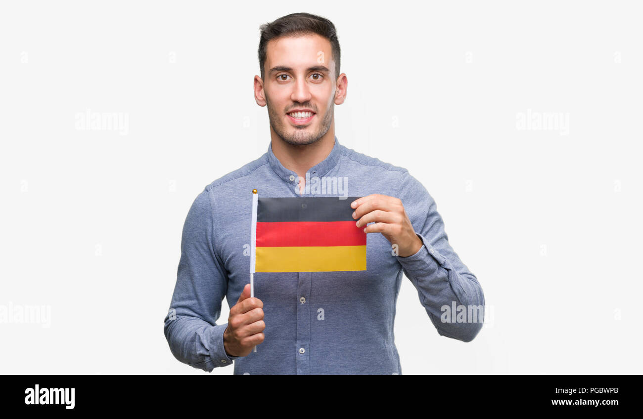 Handsome young man holding a flag of Germany with a happy face standing ...