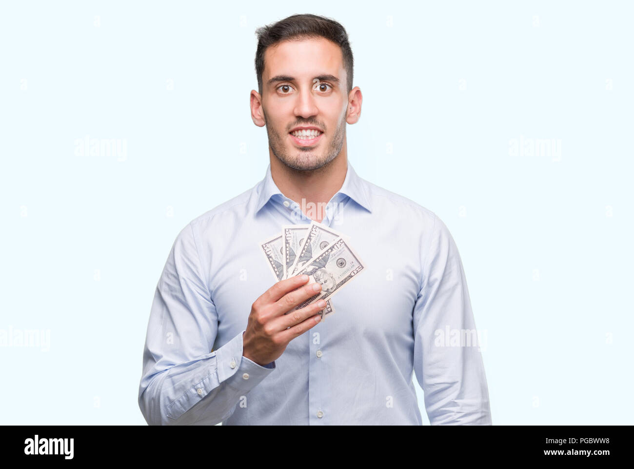 Handsome young man holding money with a happy face standing and smiling ...