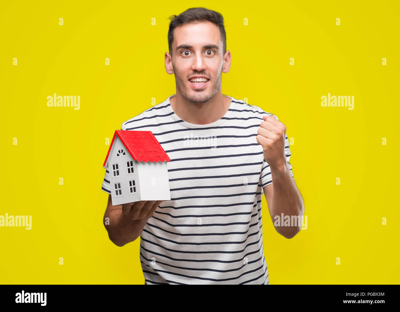 Handsome real estate agent holding a house screaming proud and ...
