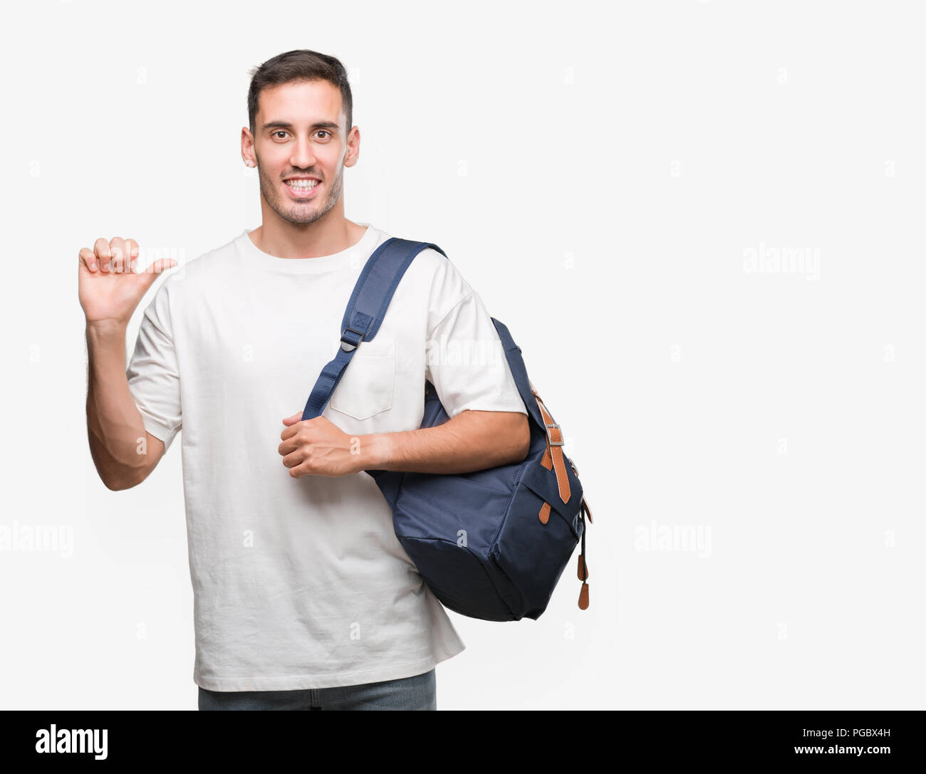 Handsome young man holding backpack pointing with hand and finger up ...