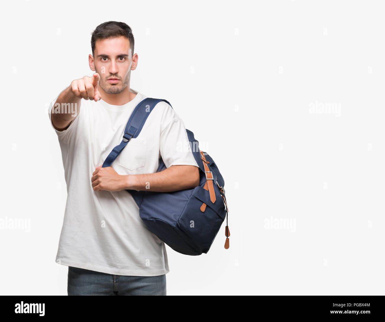 Handsome young man holding backpack pointing with finger to the camera ...