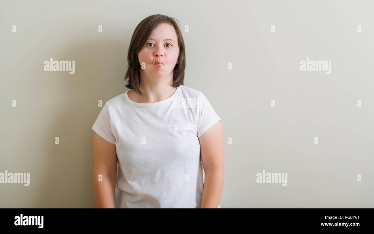 Down syndrome woman standing over wall making fish face with lips ...