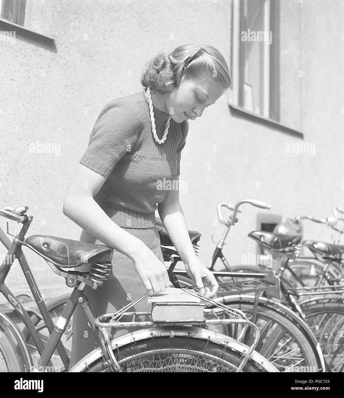 1940s woman with a bicycle. A young woman and student, places her books ...
