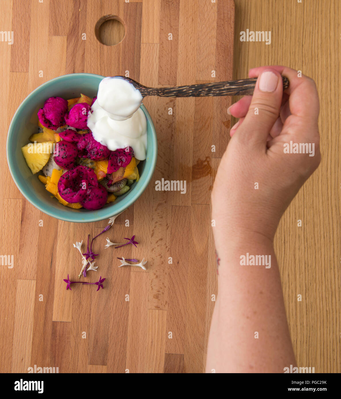hand serving yogurt to a bowl of fruits, wooden background Stock Photo ...