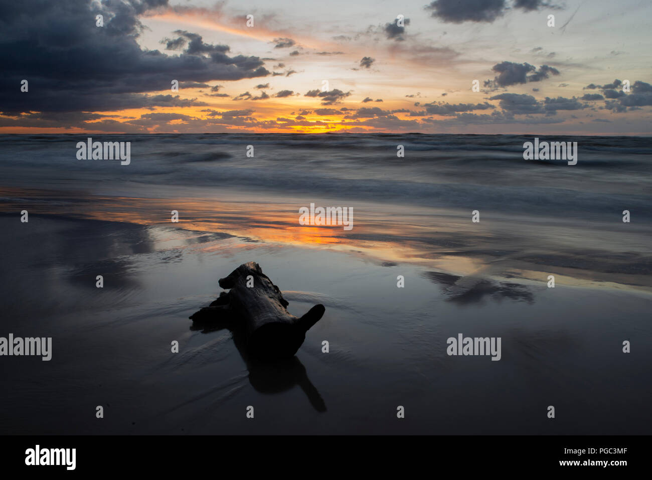 romantic sunset on the beach with wood on the sand Stock Photo - Alamy