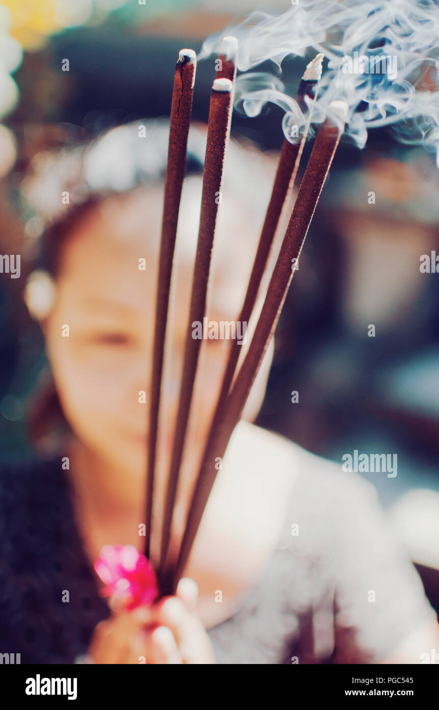 Beautiful Asian woman holding incense sticks and praying during Hindu ...